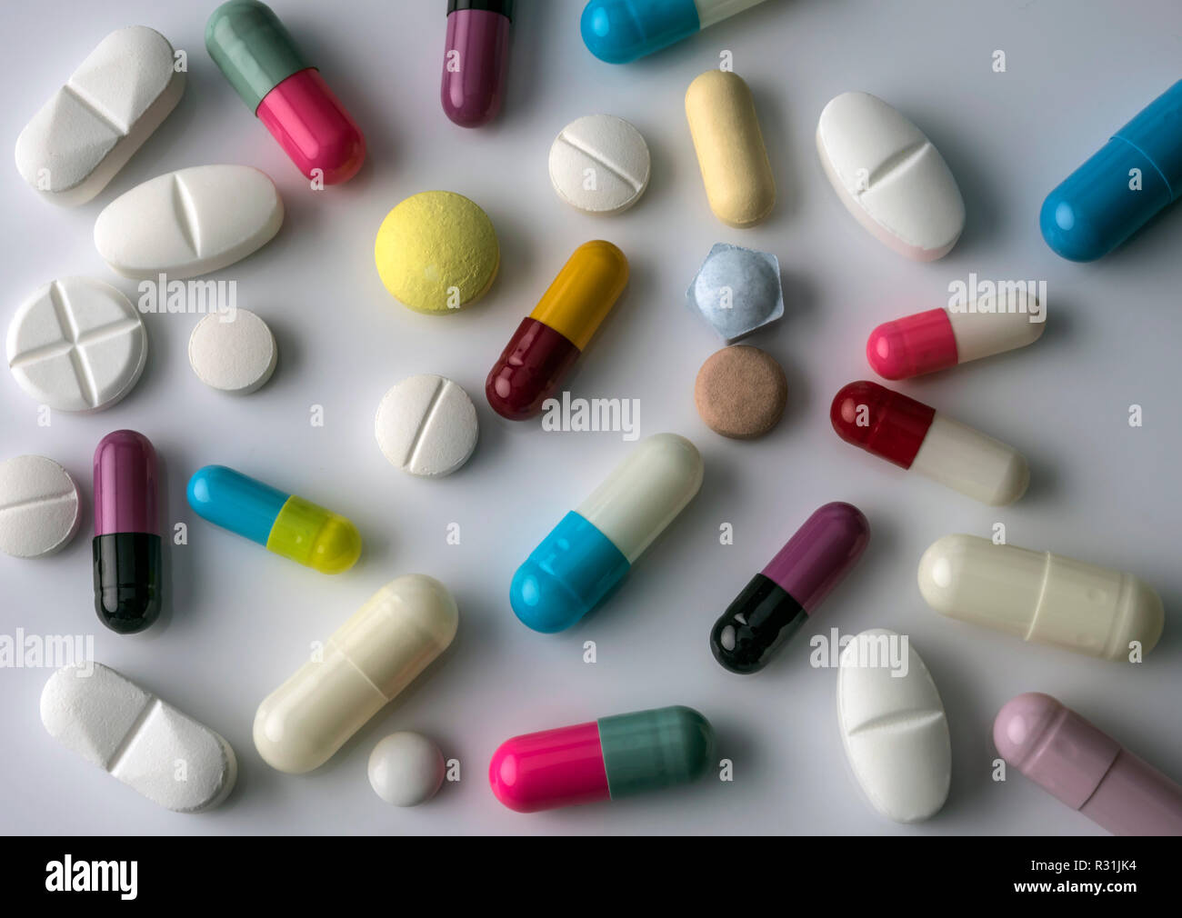 Tablets and capsules of different size and color, conceptual image ...