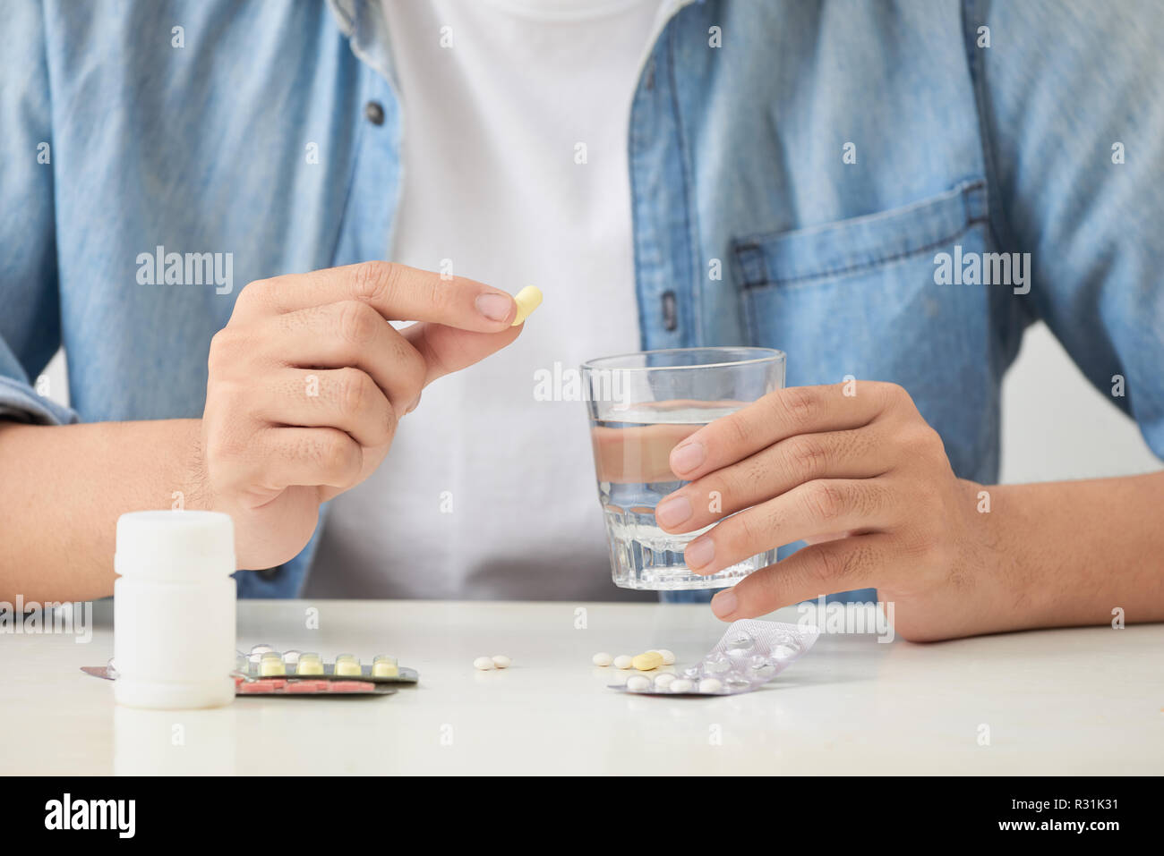 Man taking his pills on couch in the living room Stock Photo - Alamy