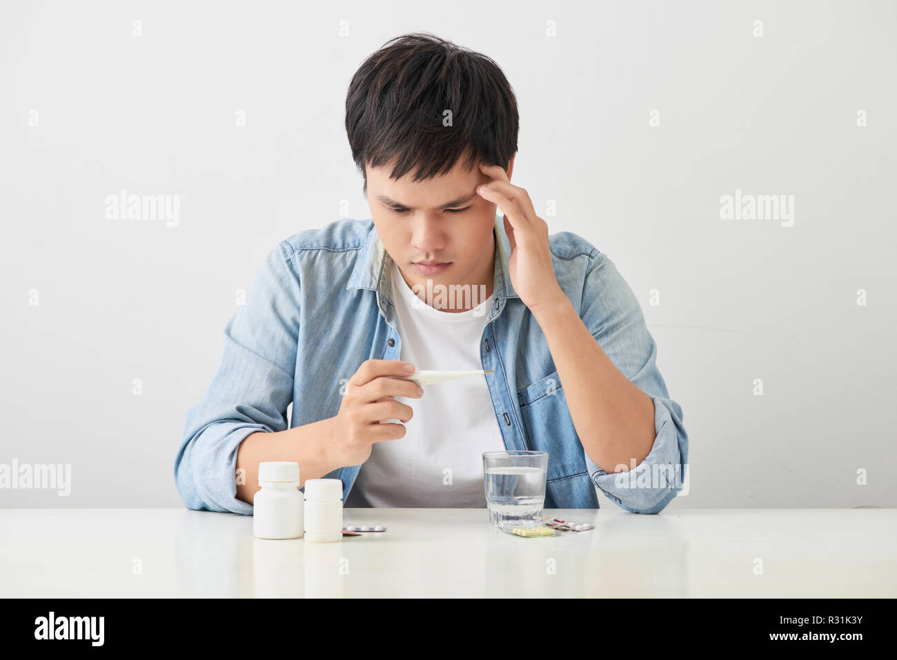 Sick young man looks at a thermometer Stock Photo - Alamy