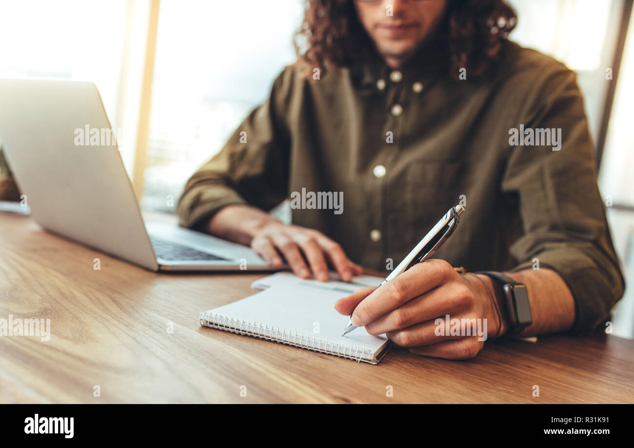 Entrepreneur making notes sitting at his work desk in office ...