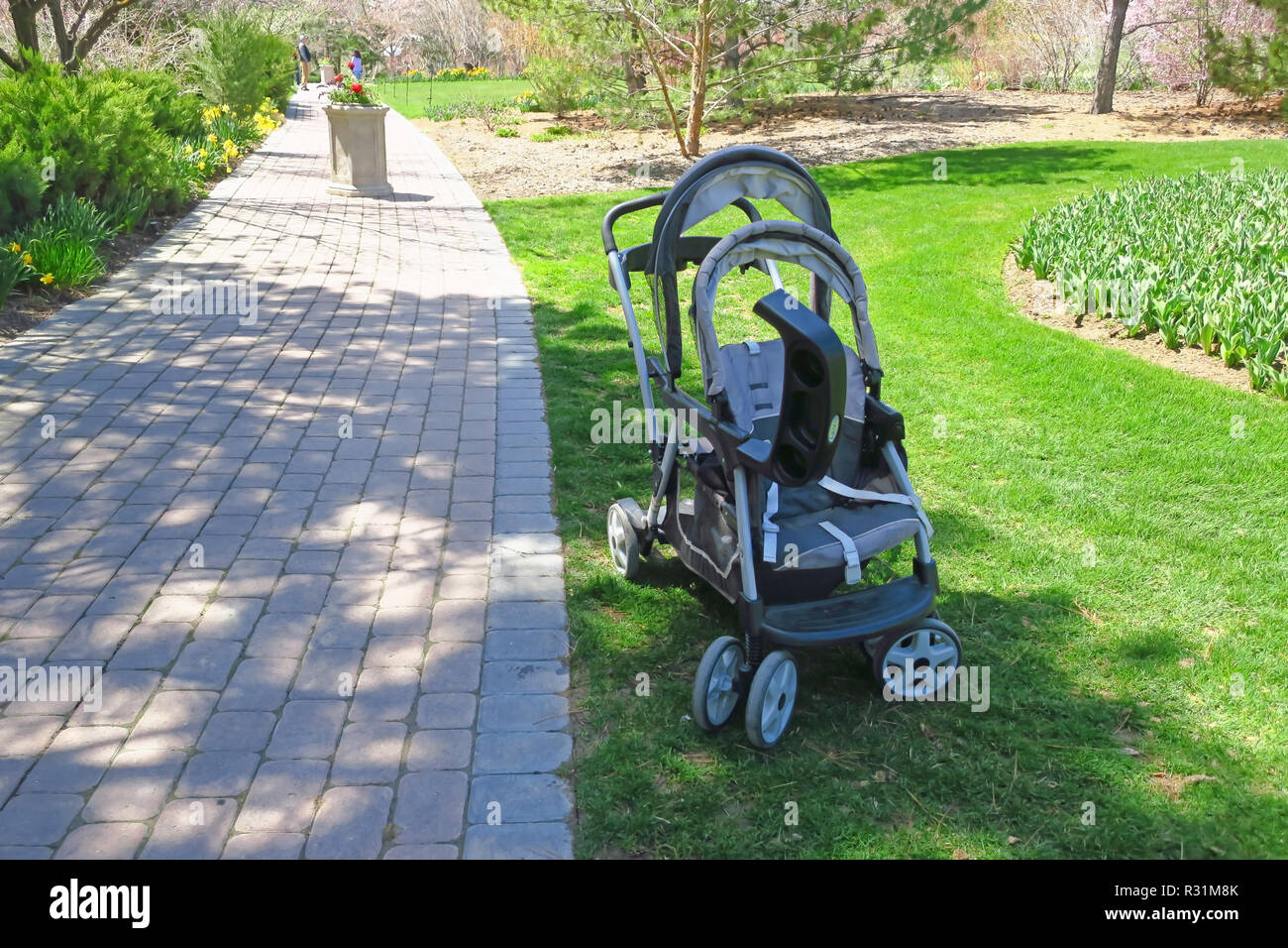 An empty stroller sitting in the grass beside a walking path Stock ...
