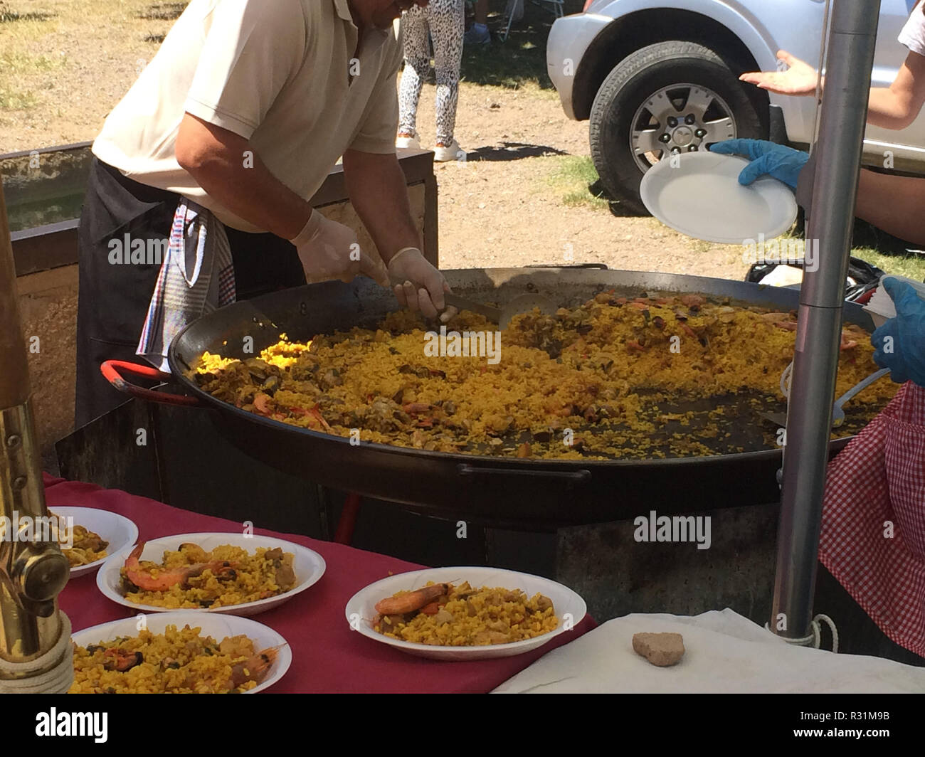 A man cooks and serves spanish paella outdoors in a big dish. Popular ...