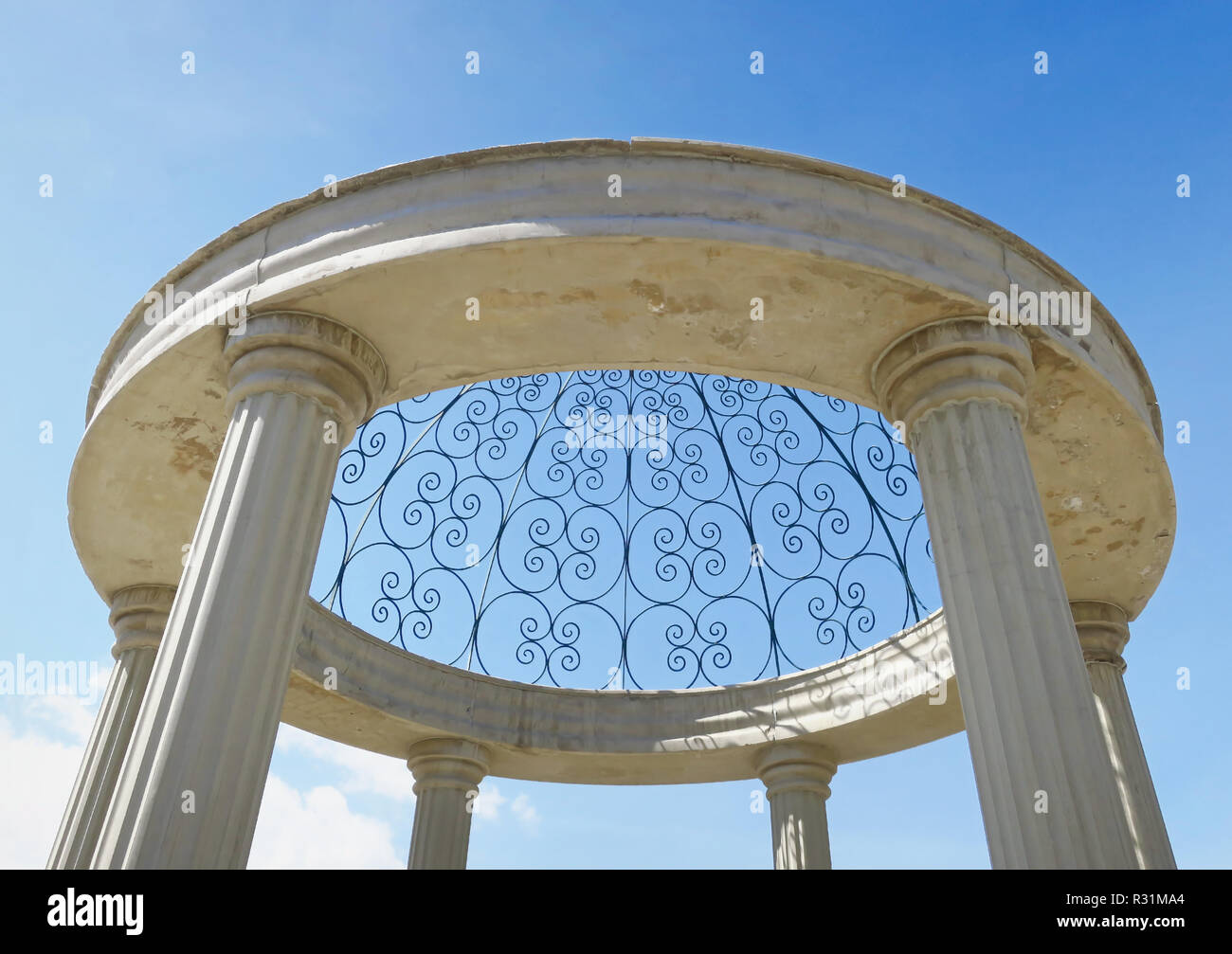 A round, decorative concrete with large pillars on a bright blue sky ...