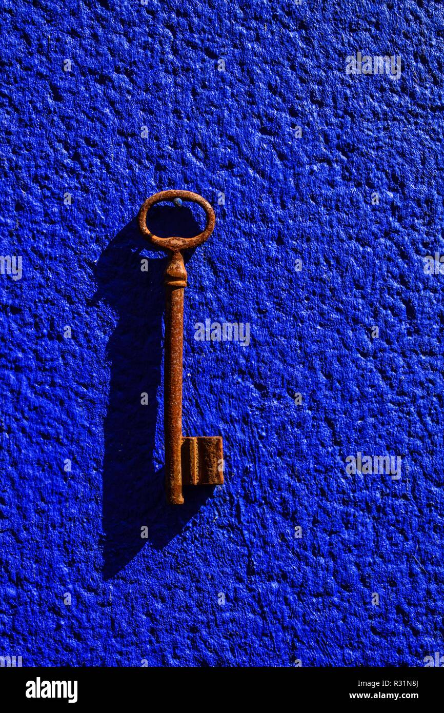 Rusty brass key on the blue wall Stock Photo - Alamy