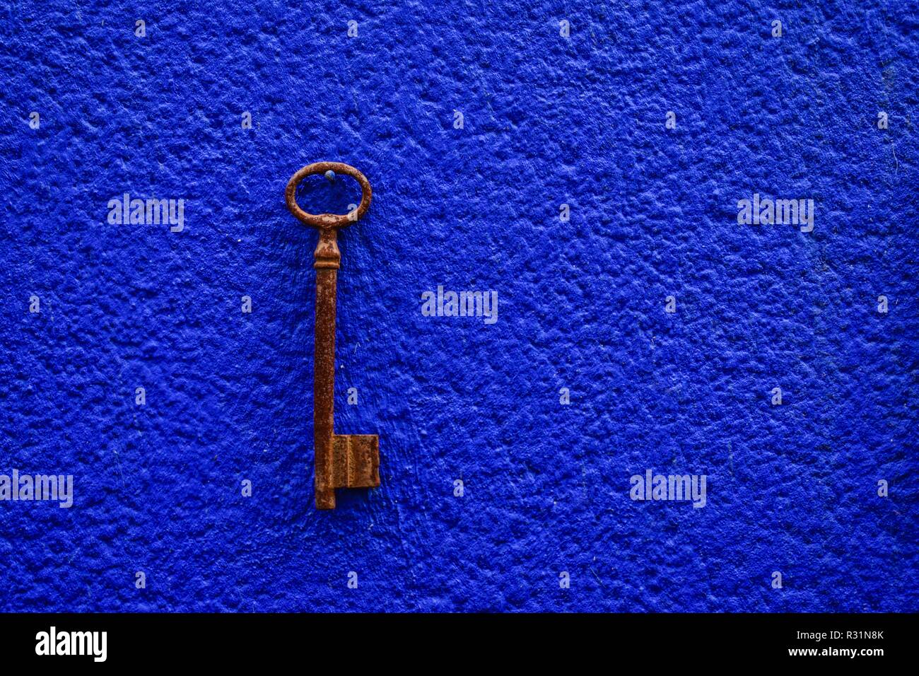 Rusty brass key on the blue wall Stock Photo - Alamy