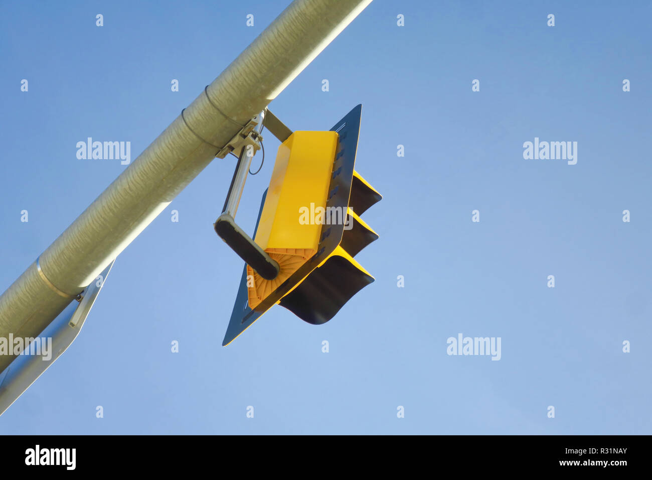 A yellow traffic light suspended on a pole on a bright blue sky Stock ...