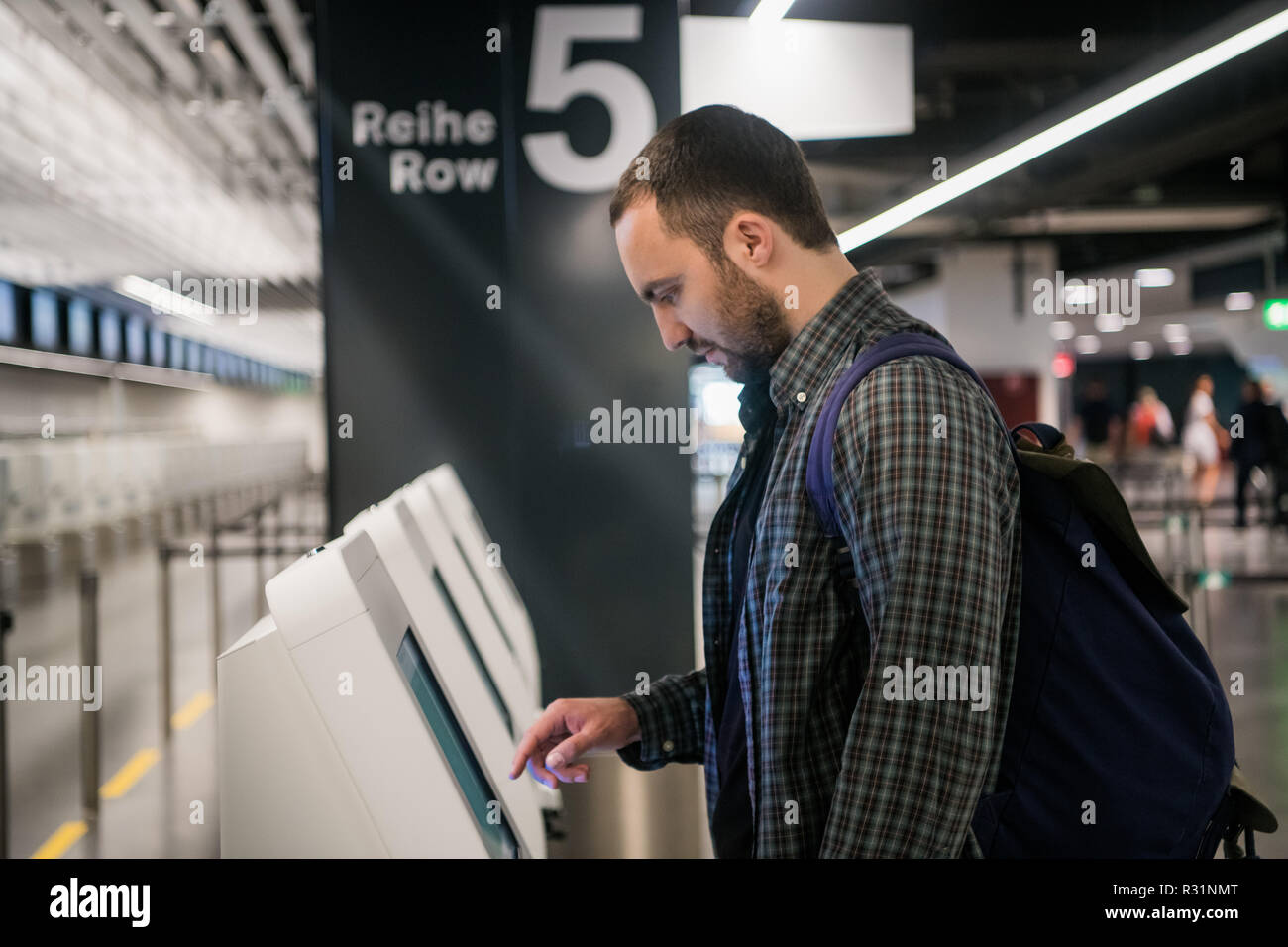Pensive man using the check-in machine at the airport getting the ...