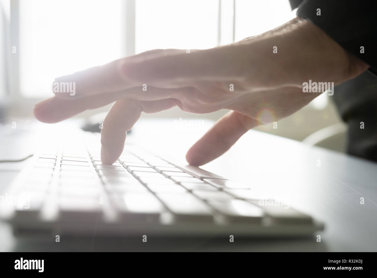 Businessman hand typing on black computer keypad lit by bright sun ...