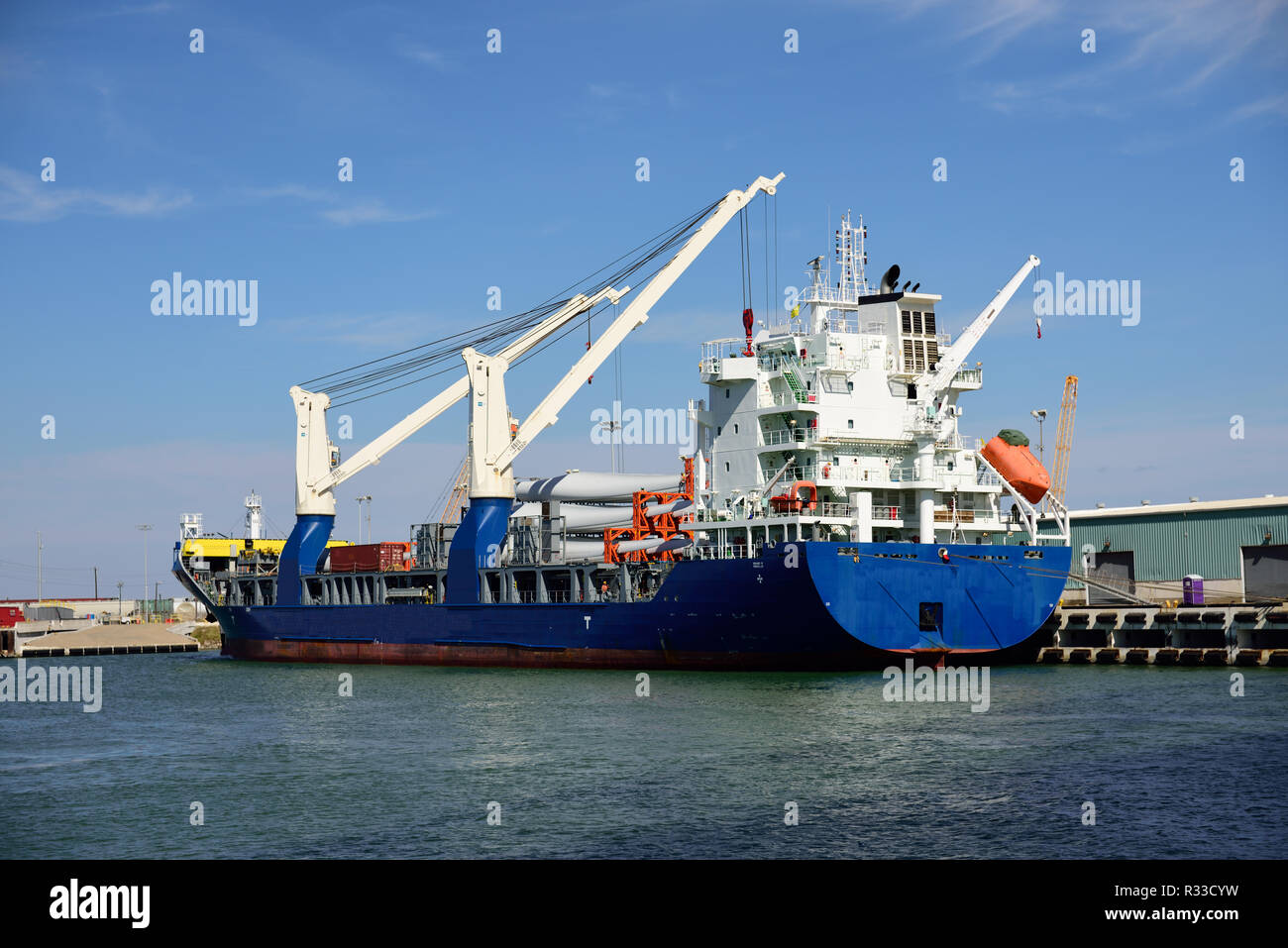 Larrge cargo freighter at a dock unloading 36 meter wind energy turbine ...