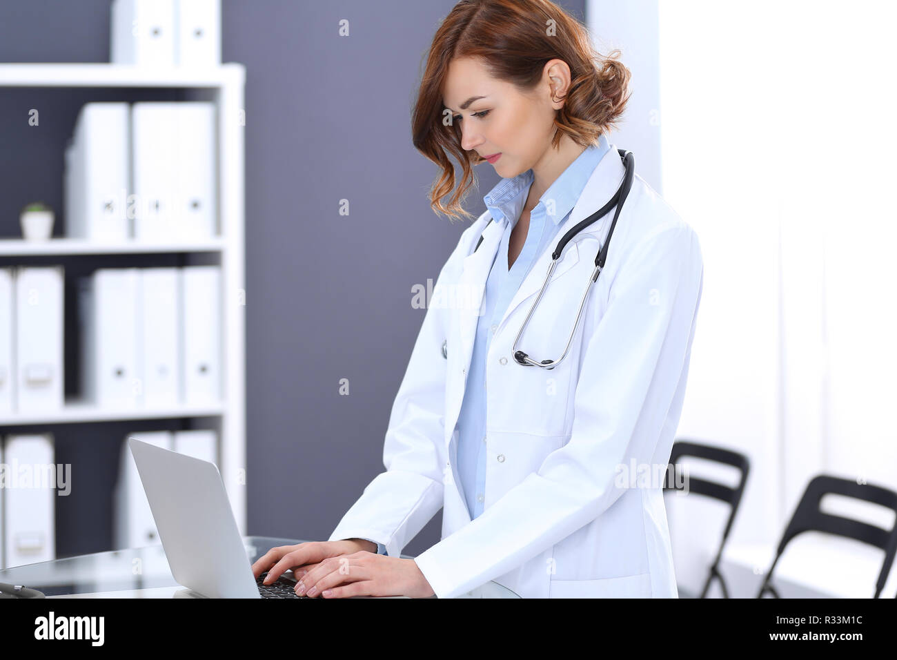 Happy doctor woman at work. Portrait of female physician using laptop ...