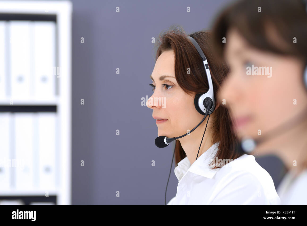 Call center. Group of operators at work. Focus on young brunette woman. Business concept Stock ...