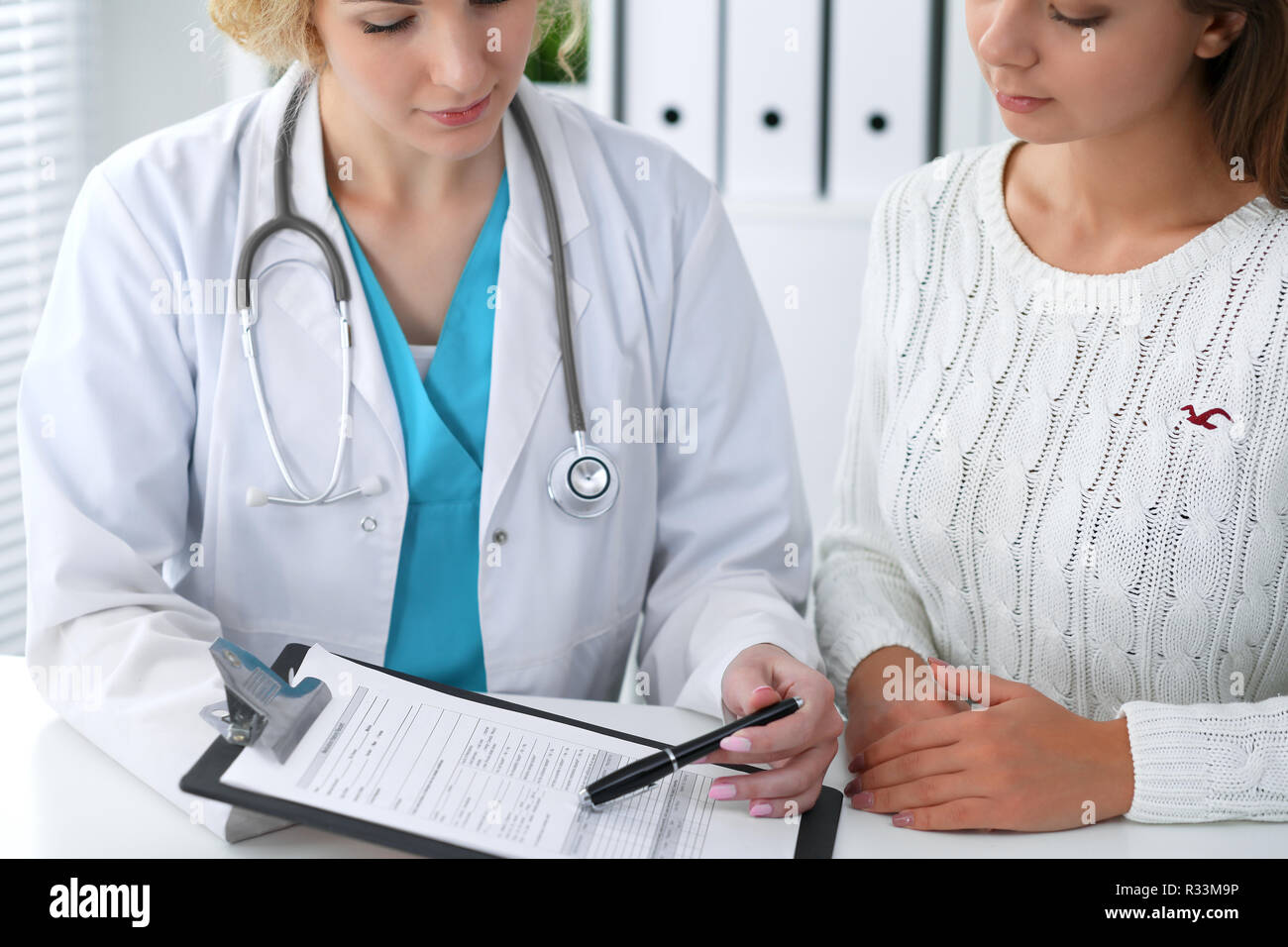 Happy blonde female doctor and patient discussing medical examination ...