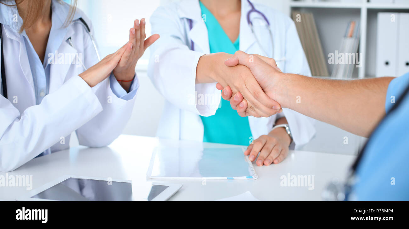 Two doctors shaking hands to each other at meeting. Teamwork and ...