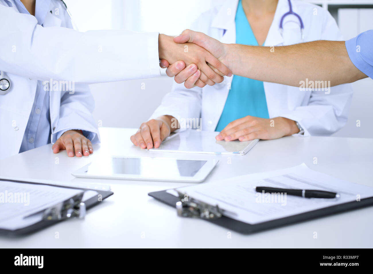 Two doctors shaking hands to each other at meeting. Teamwork and ...