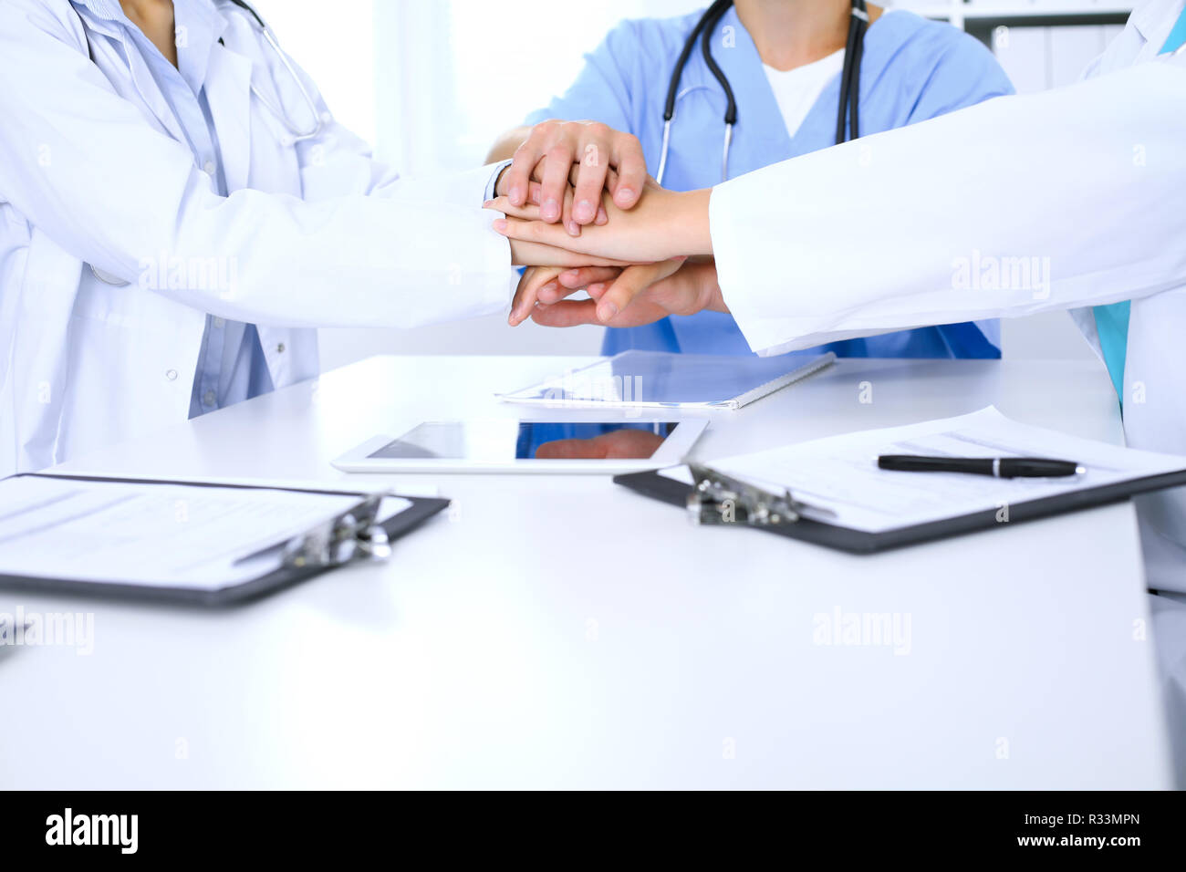 Group of doctors joining hands at meeting. Teamwork and success in ...