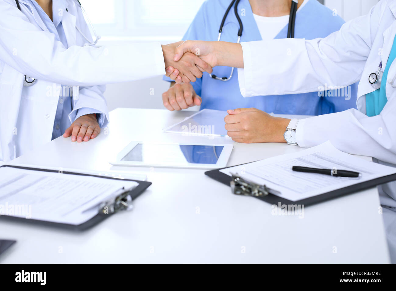 Two doctors shaking hands to each other at meeting. Teamwork and ...