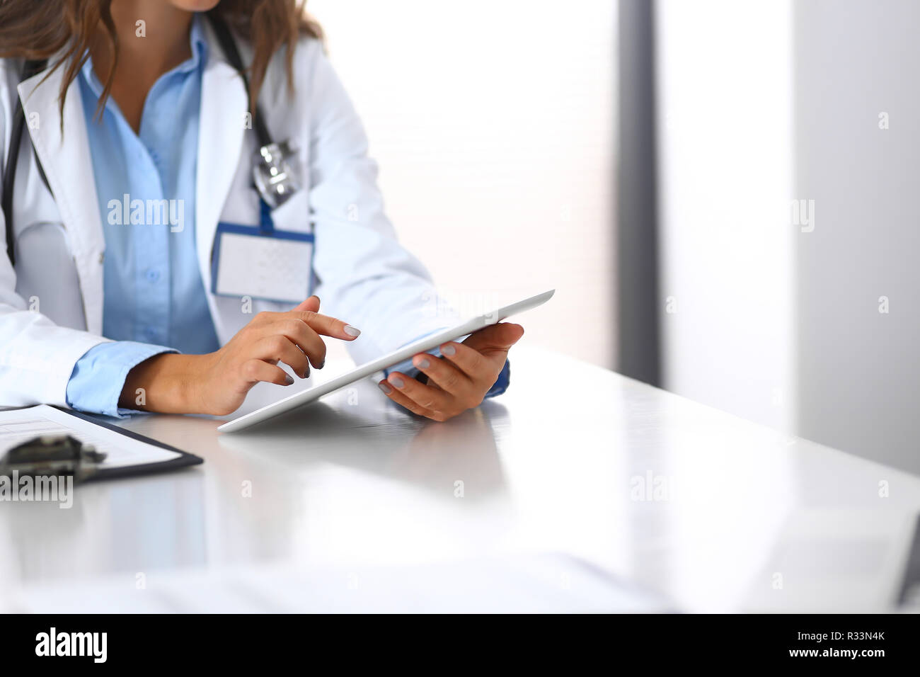 Unknown doctor woman using tablet computer while standing straight near ...
