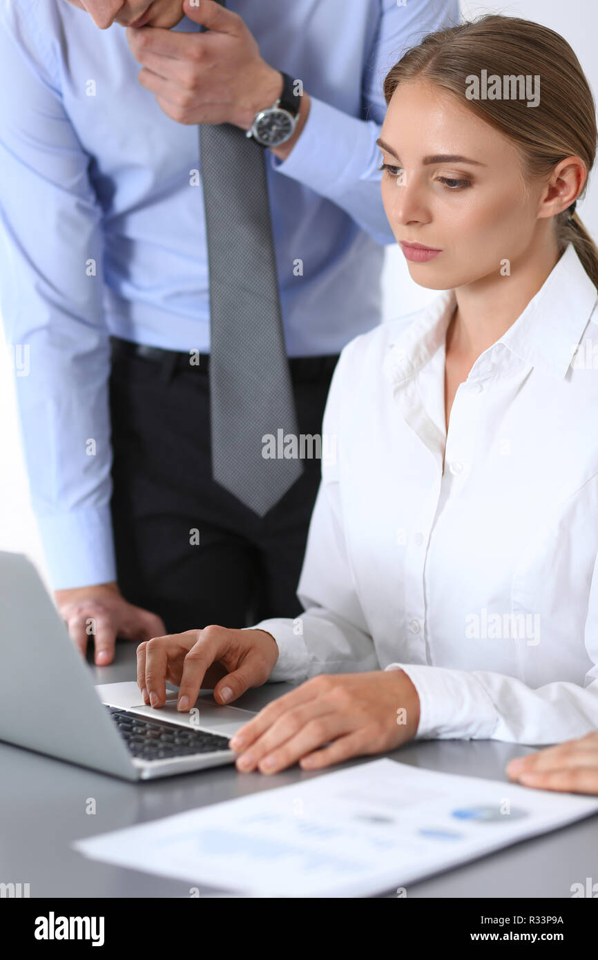 Group of business people using laptop computer while standing in office ...