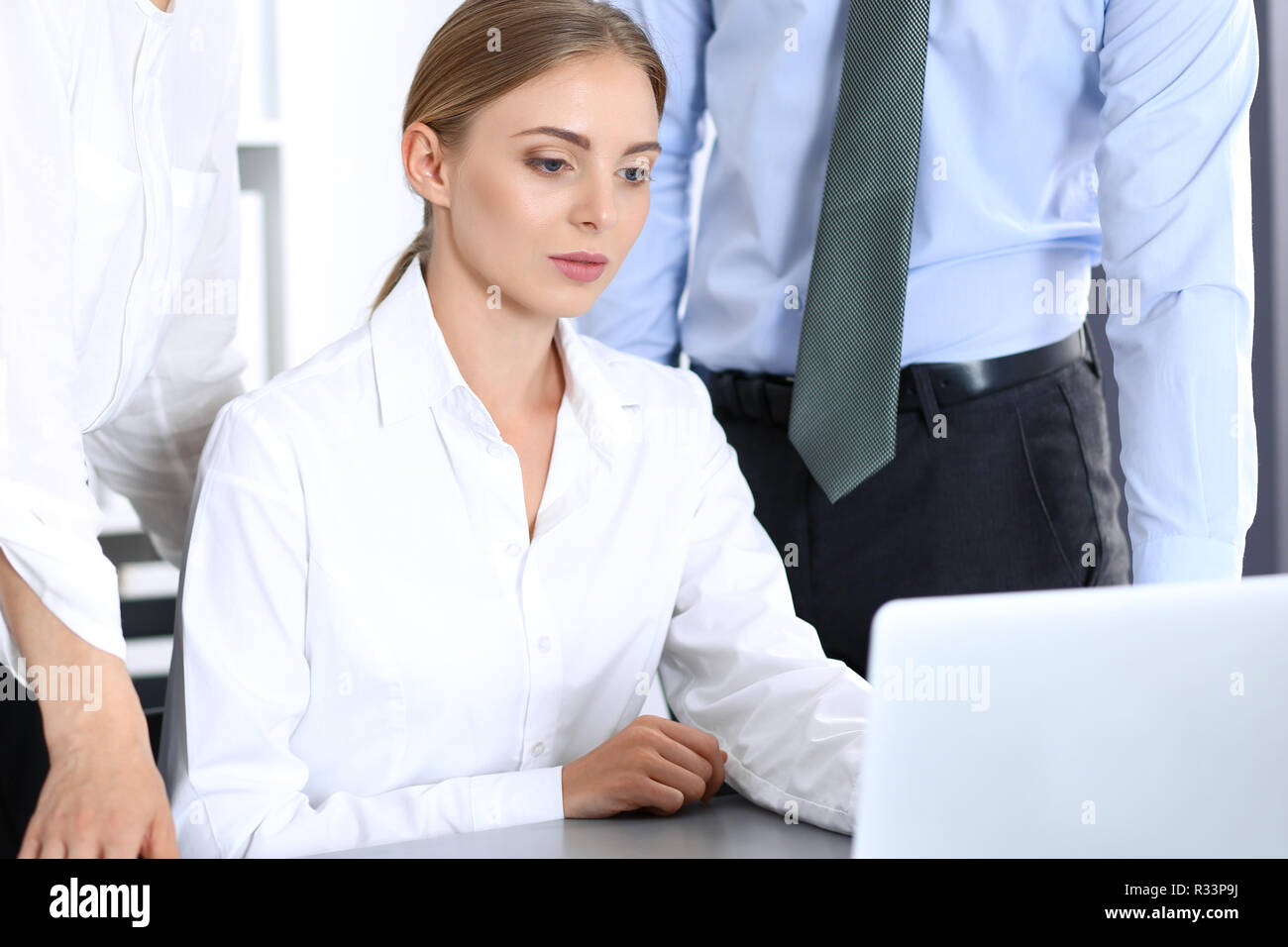 Group of business people using laptop computer while standing in office ...