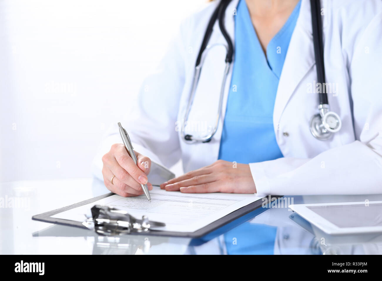 Female doctor filling up medical form on a clipboard, closeup ...