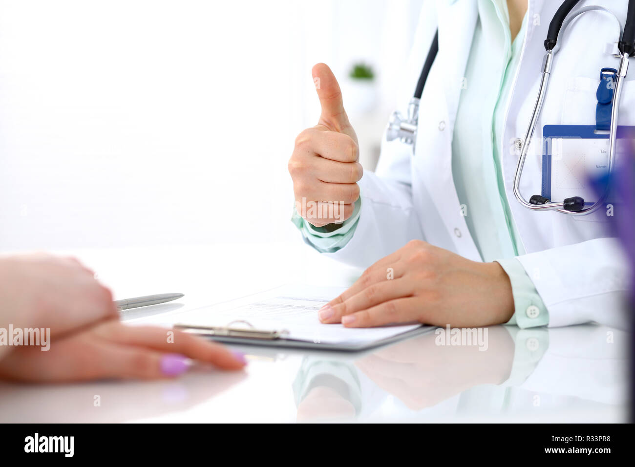 Doctor showing Ok sign with thumb up to patient while sitting at the ...