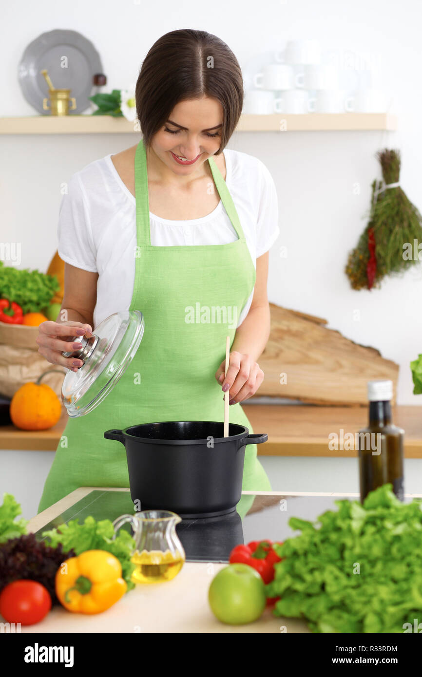 Beautiful Hispanic woman cooking soup in kitchen. Healthy meal and ...