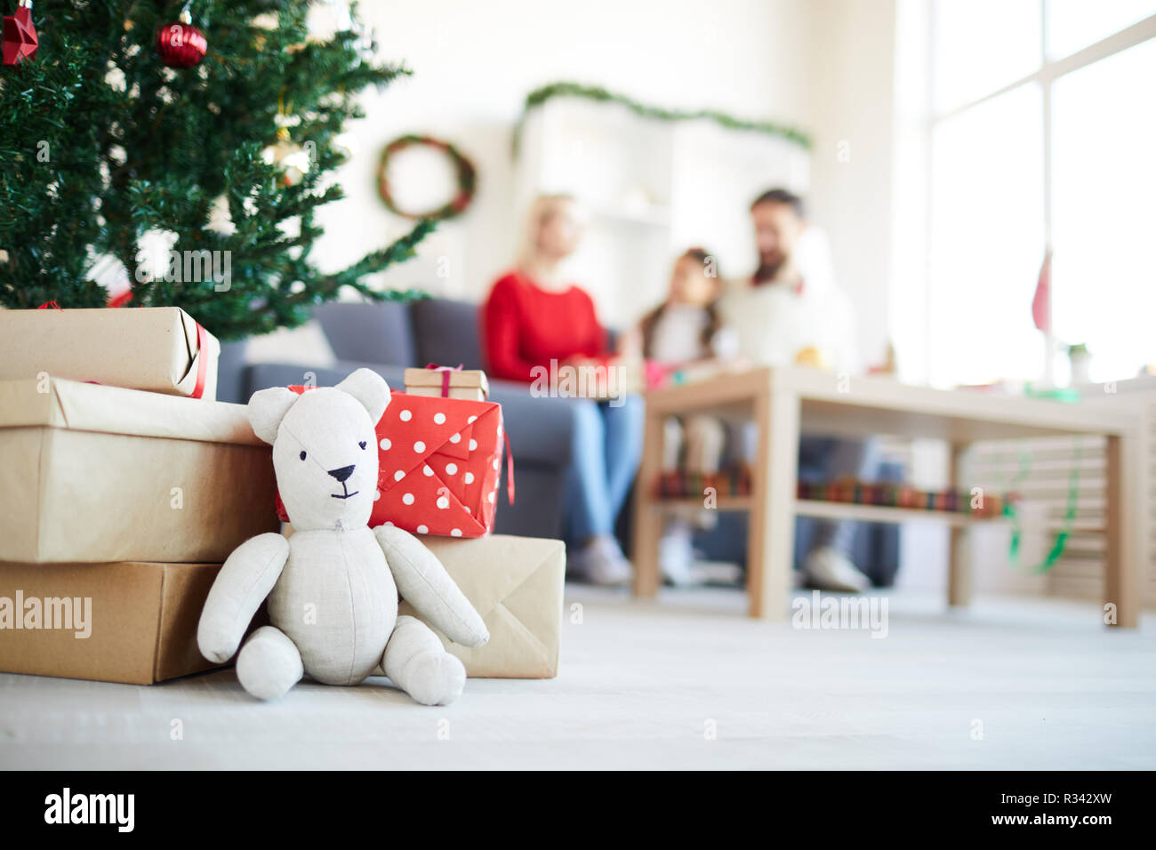 White teddybear and stack of packed gifts on the flooe by decorated ...