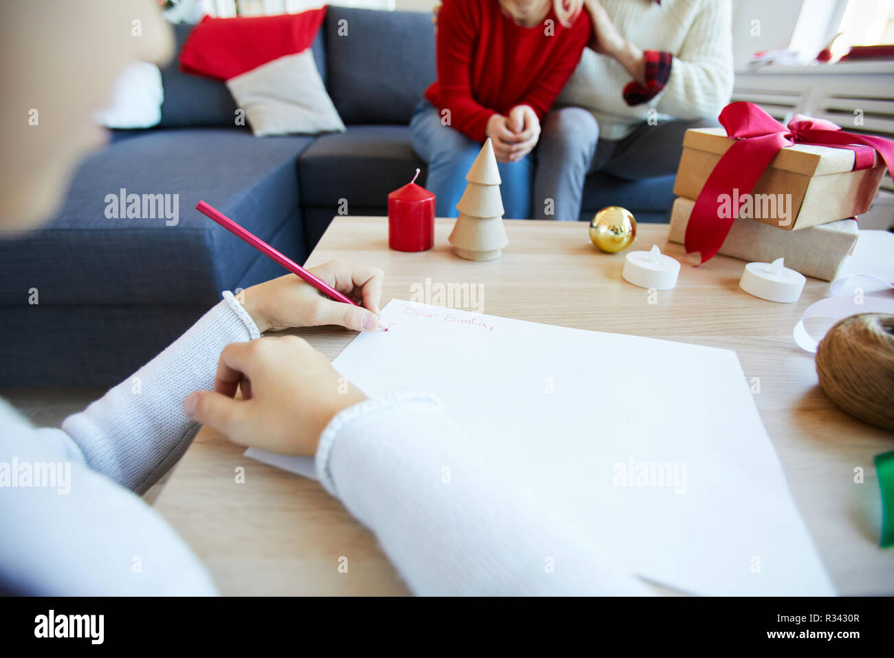 Child holding crayon while writing letter for Santa on sheet of paper ...