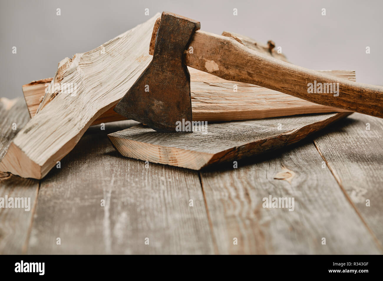 Close up view of axe and wood logs on wooden table on grey background ...