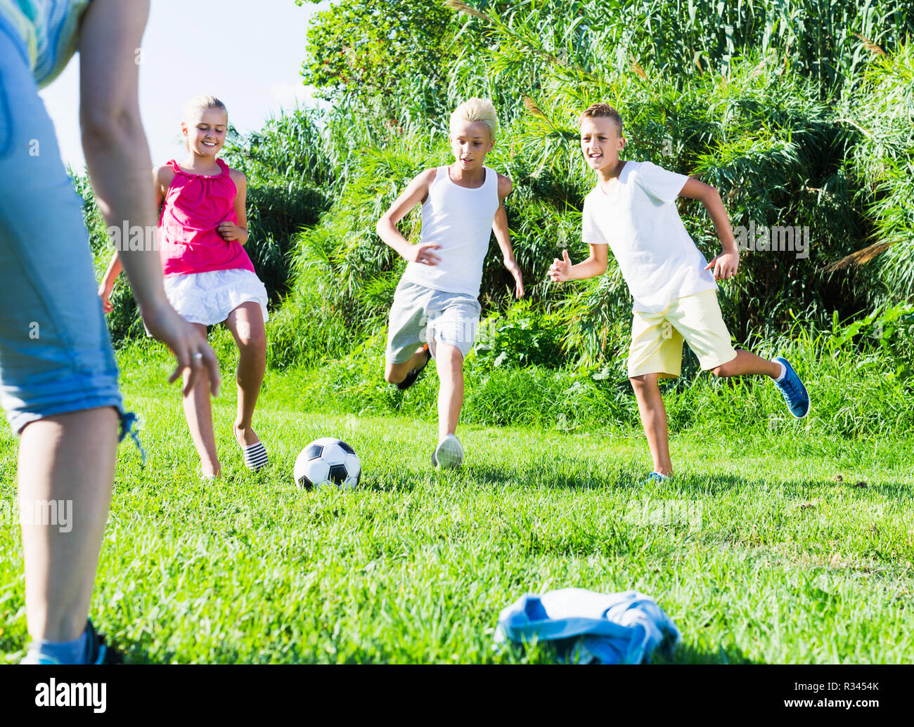 Group of smiling children having fun together outdoors playing football ...