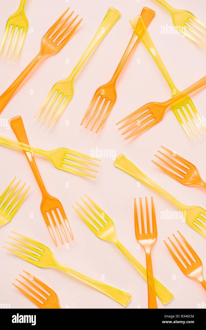 Top view of colorful orange and yellow plastic forks on pink background ...