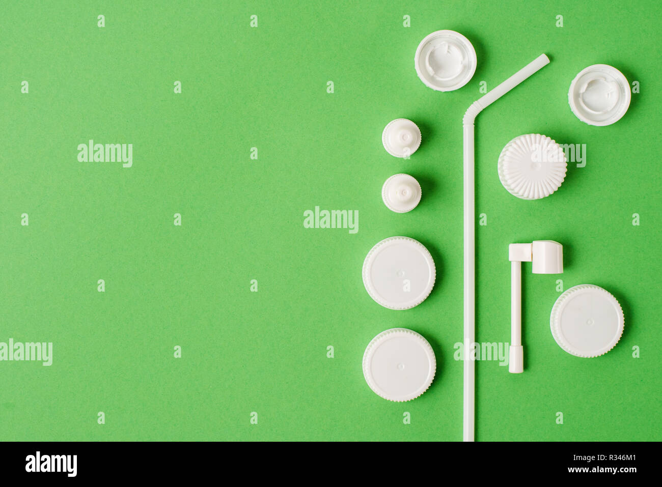 Top view of different plastic bottle caps and drinking straw on green ...