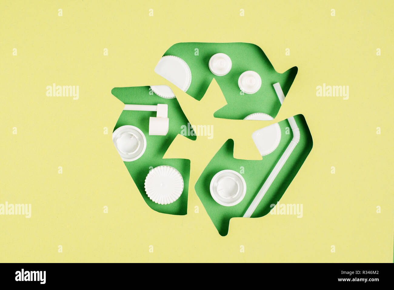 Top view of green recycle sign with bottle caps pattern on yellow ...