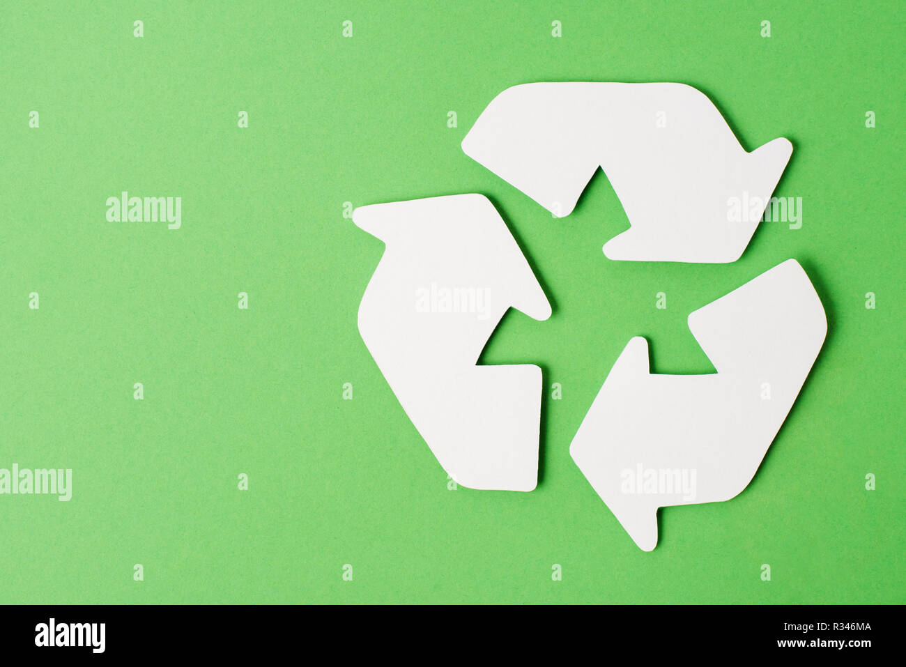 Top view of white recycle sign on green background Stock Photo - Alamy