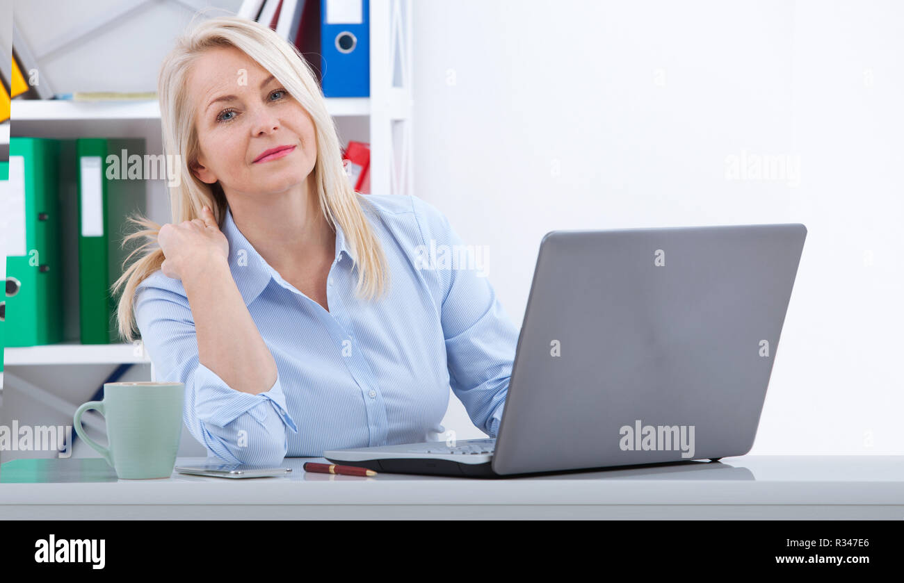 Pretty middle aged business woman working on computer in her office ...
