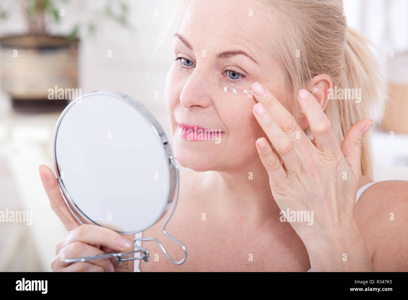 Forty years old woman looking at wrinkles in mirror. Plastic surgery ...