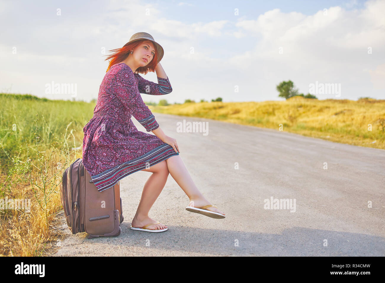 Very Pretty Woman In Summer Dress And Hat Hitchhiking With Suitcase On The Road Beauty Woman