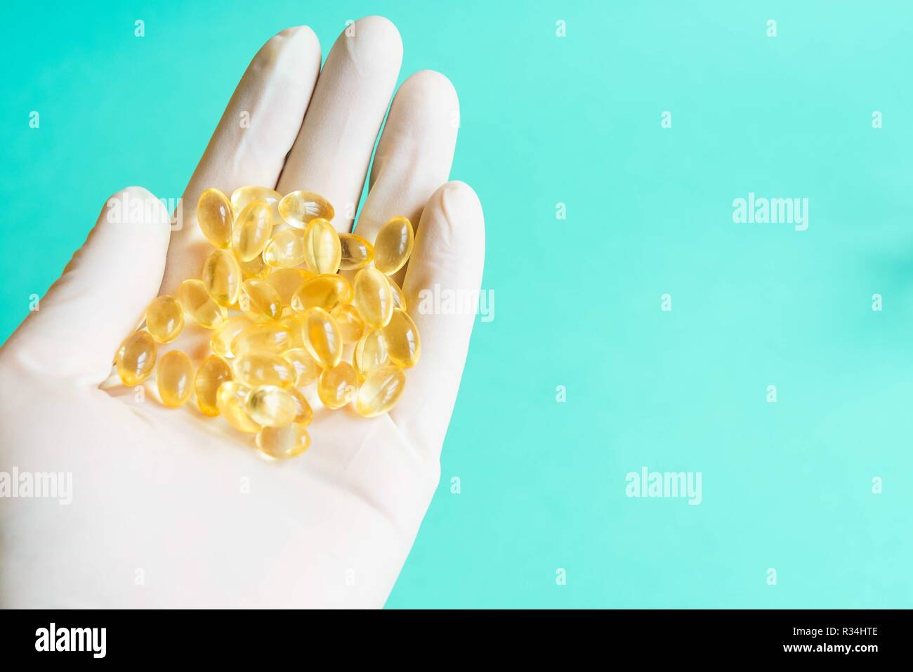 Yellow pills in a doctor's hand in a glove on a green background ...