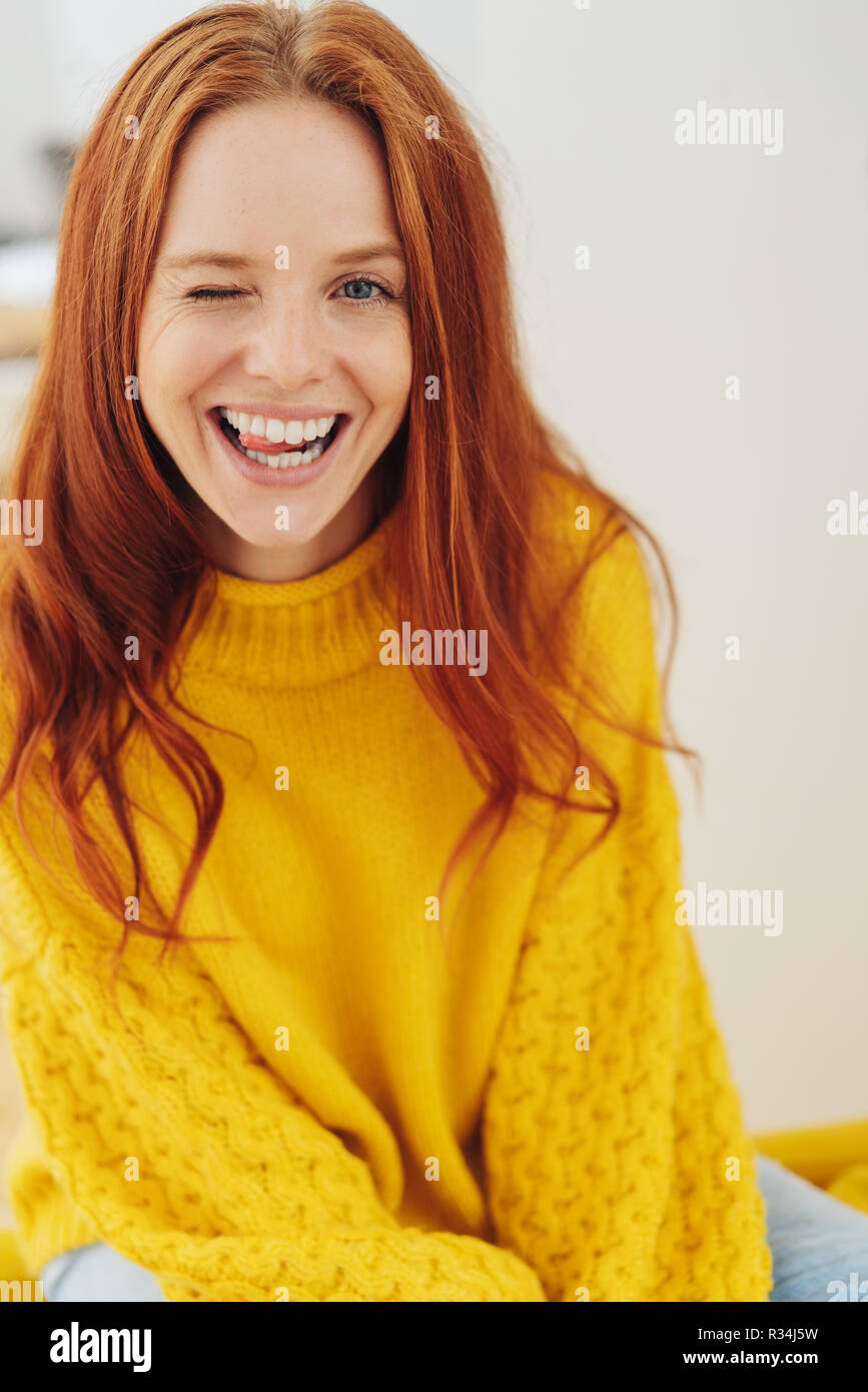 Sassy Attractive Young Redhead Woman Winking Playfully At Camera With