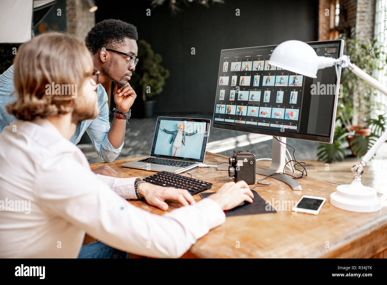 Two male photographers choosing woman's portraits at the working place ...