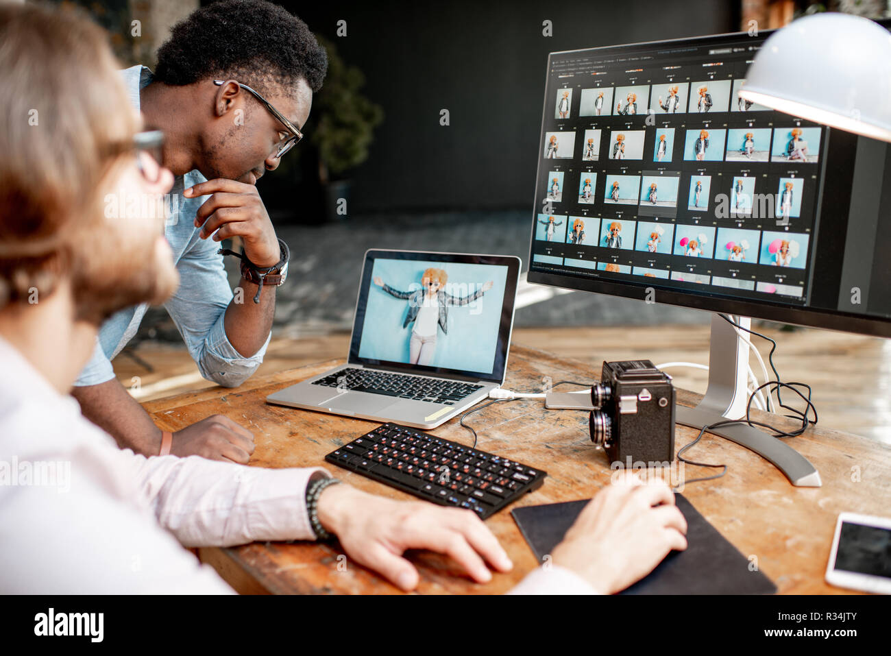 Two male photographers choosing woman's portraits at the working place ...