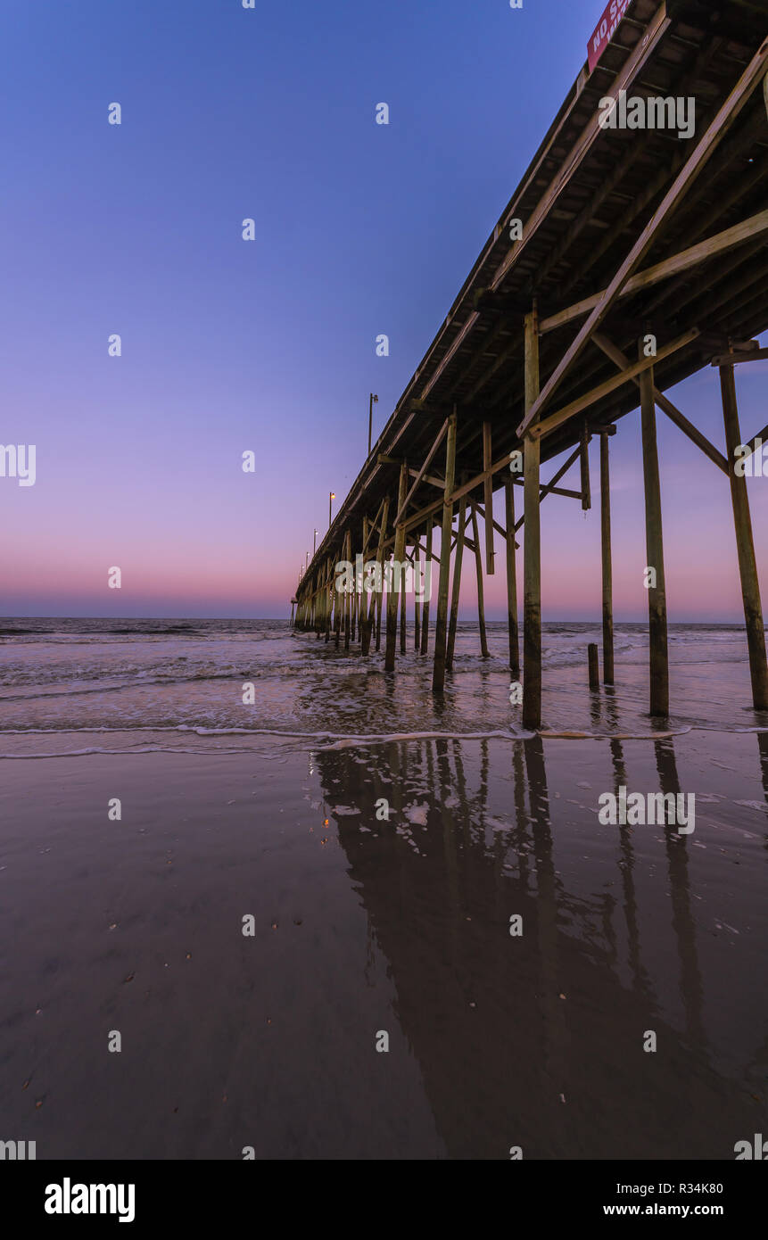 Purple & pink sky during sunset at a beach with a pier Stock Photo - Alamy