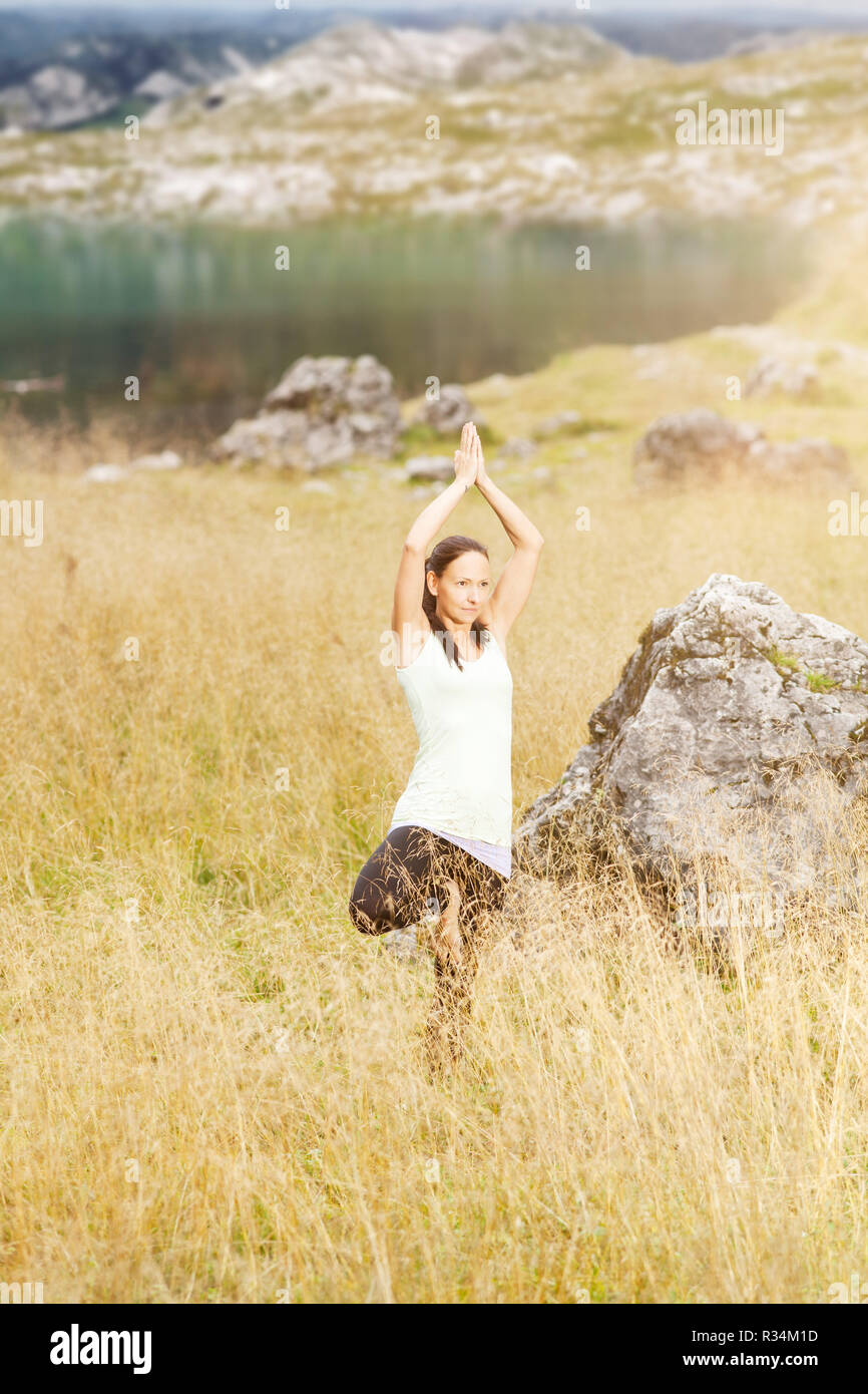 young woman doing yoga exercises in the tall grass Stock Photo - Alamy
