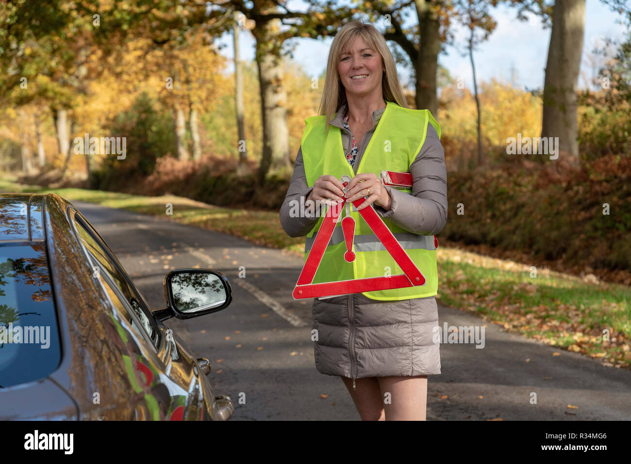 Female motorist putting out a reflective safety triangle following a ...