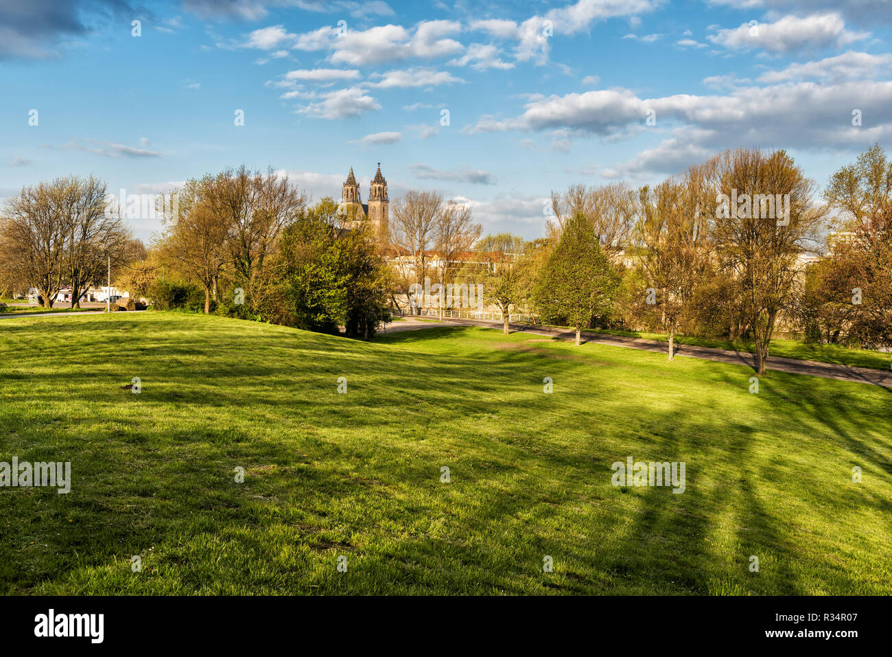 City park of Magdeburg with cathedral, green grass, trees and cloudy ...