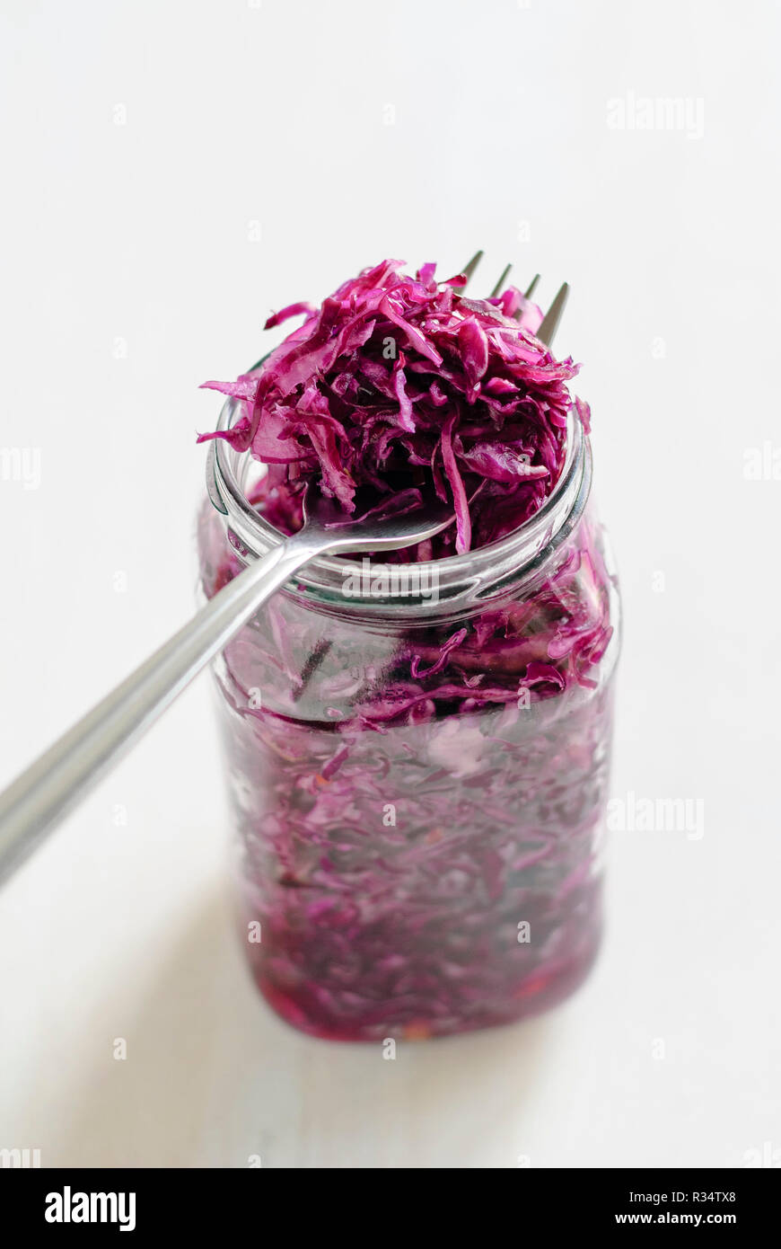 From above shot of fork lying on glass jar with yummy fermented purple ...
