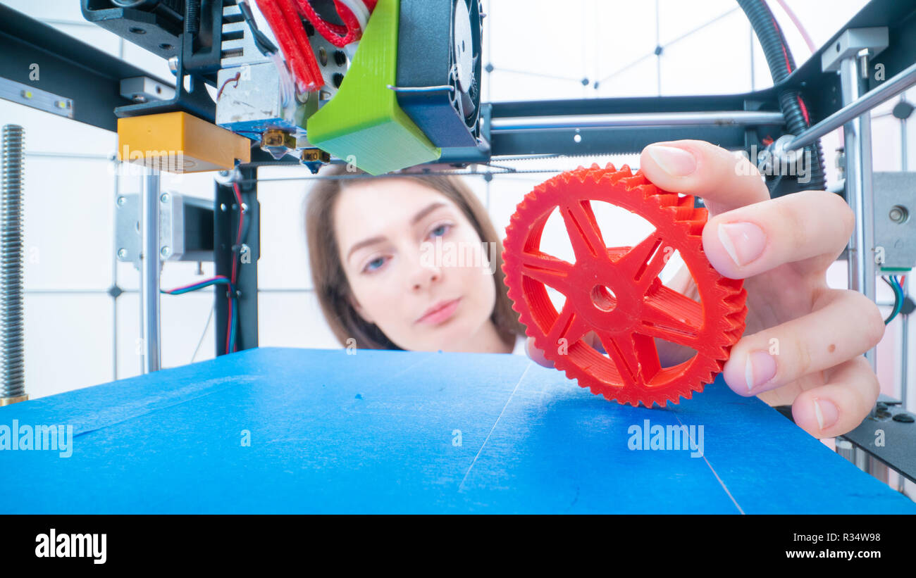 Young women designer in 3d printing lab. Girl takes the finished detail ...