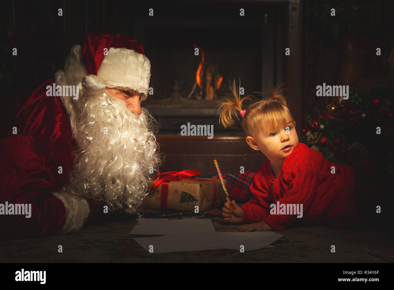 Real Santa Claus is playing with children near the Christmas tree. The ...
