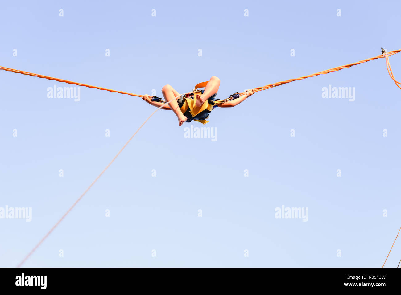 Child jumping very high in elastic trampoline , seen from below and ...