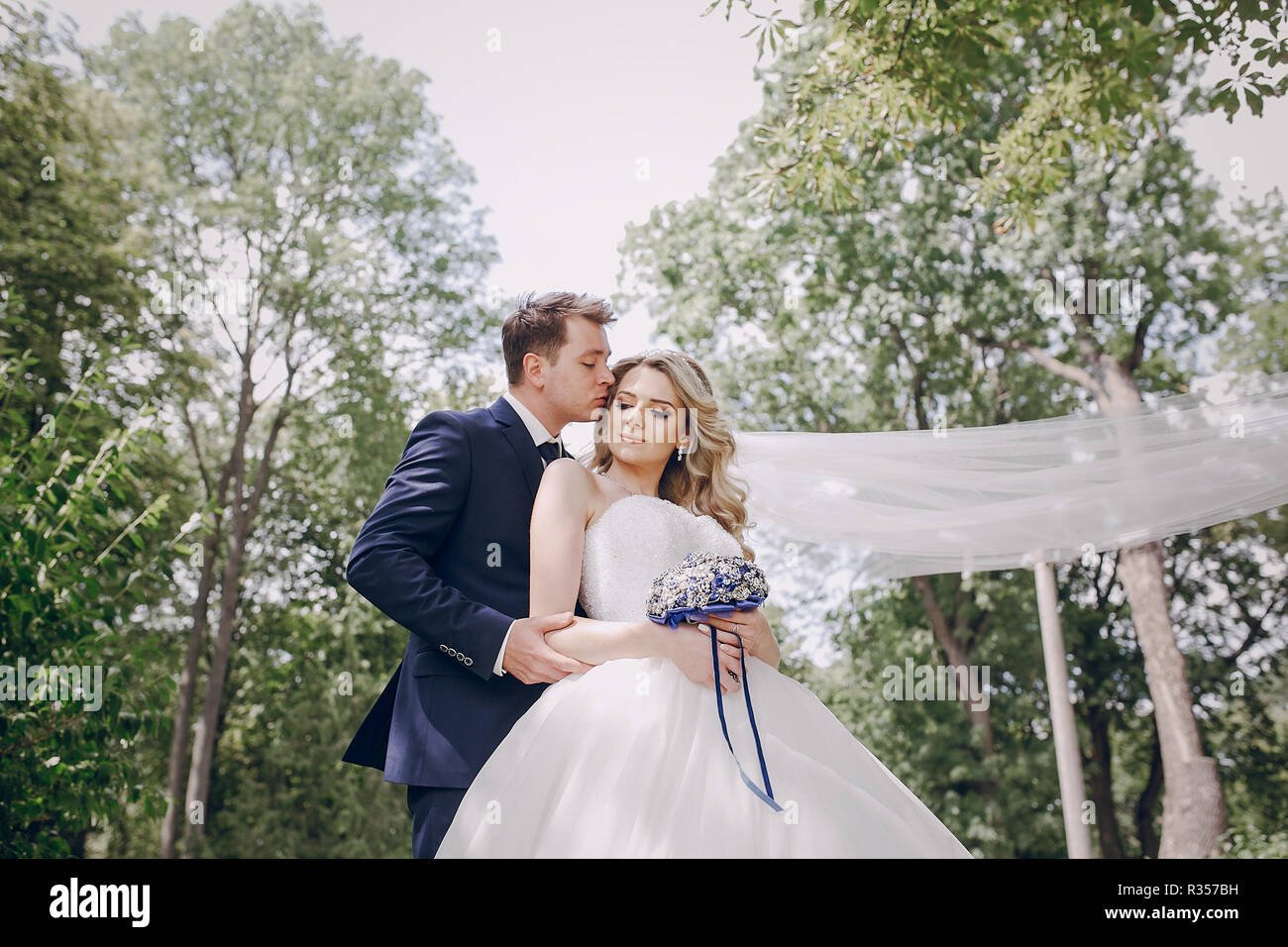 Bridal veil wedding couple hugs kisses outdoors Stock Photo - Alamy